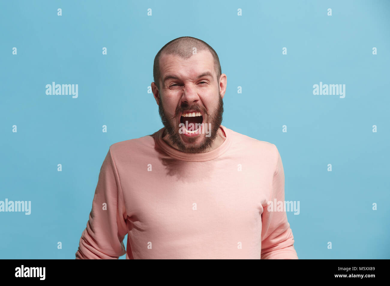 The young emotional angry man screaming on blue studio background Stock ...