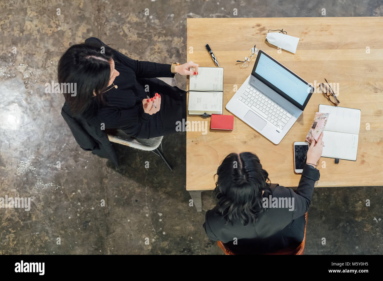 overhead view two young women indoor sitting working desk - business ...
