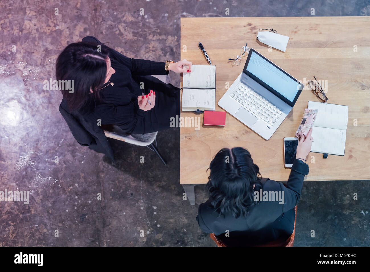 overhead view two young women indoor sitting working desk - business ...