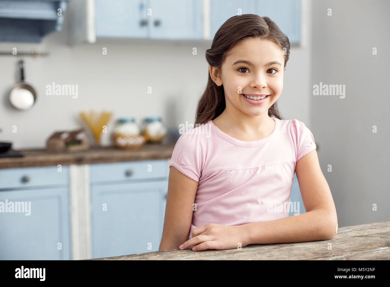Alert little girl sitting in the kitchen Stock Photo - Alamy