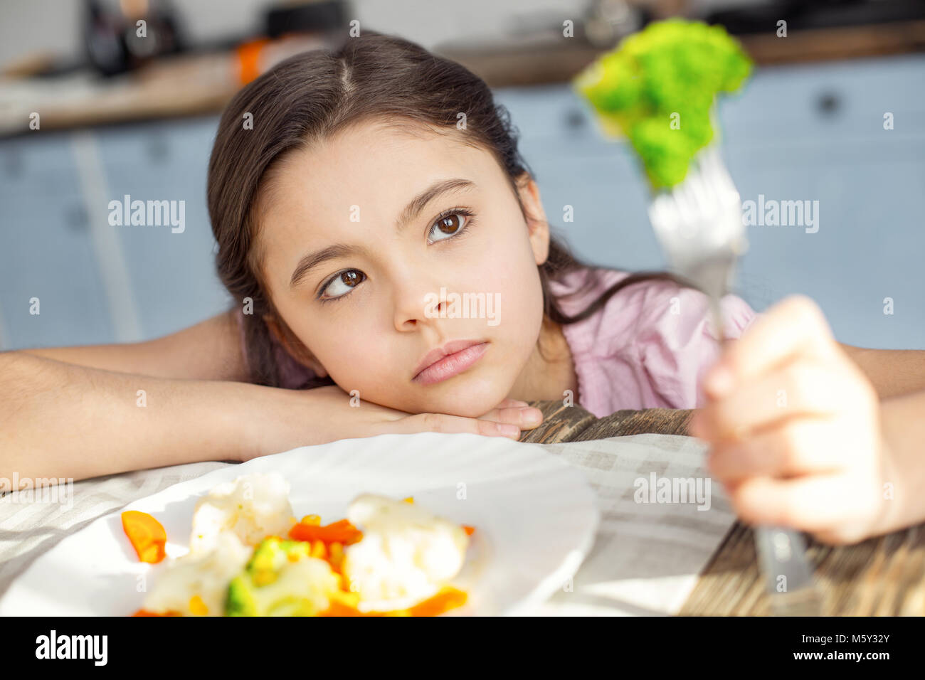 Upset child looking at the vegetable on her fork Stock Photo - Alamy