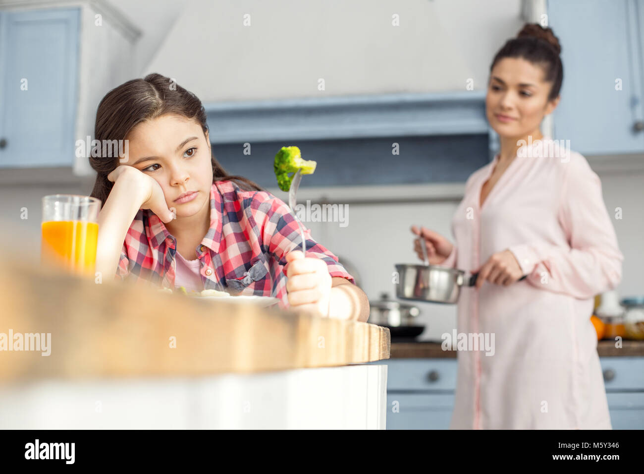 Unhappy girl eating tasteless vegetables for breakfast Stock Photo - Alamy