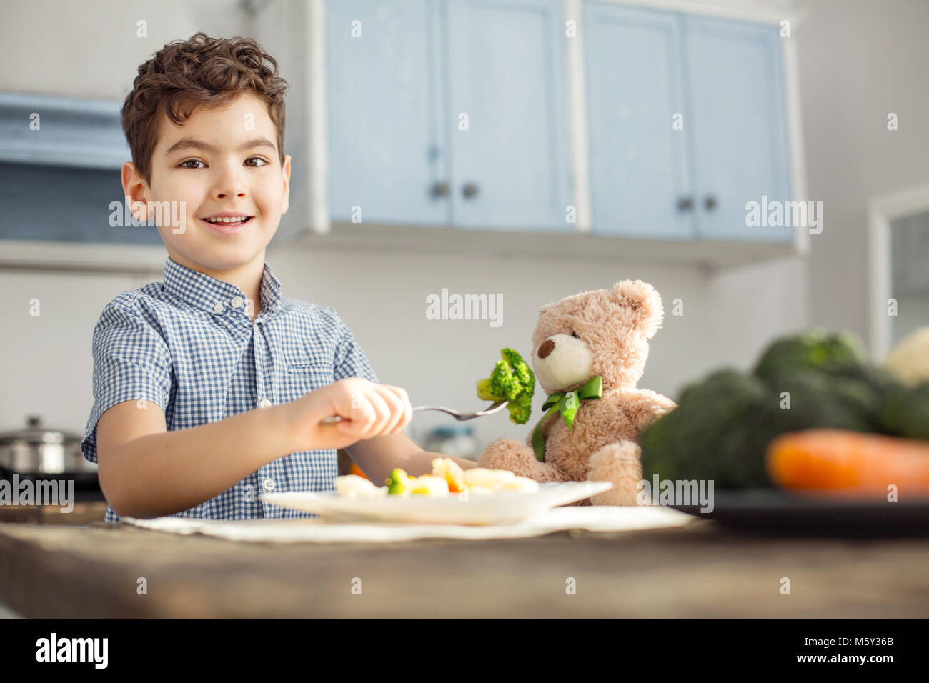 Happy boy feeding his toy with healthy food Stock Photo - Alamy