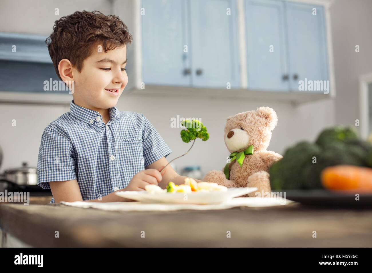 Smiling boy feeding his toy with healthy food Stock Photo - Alamy