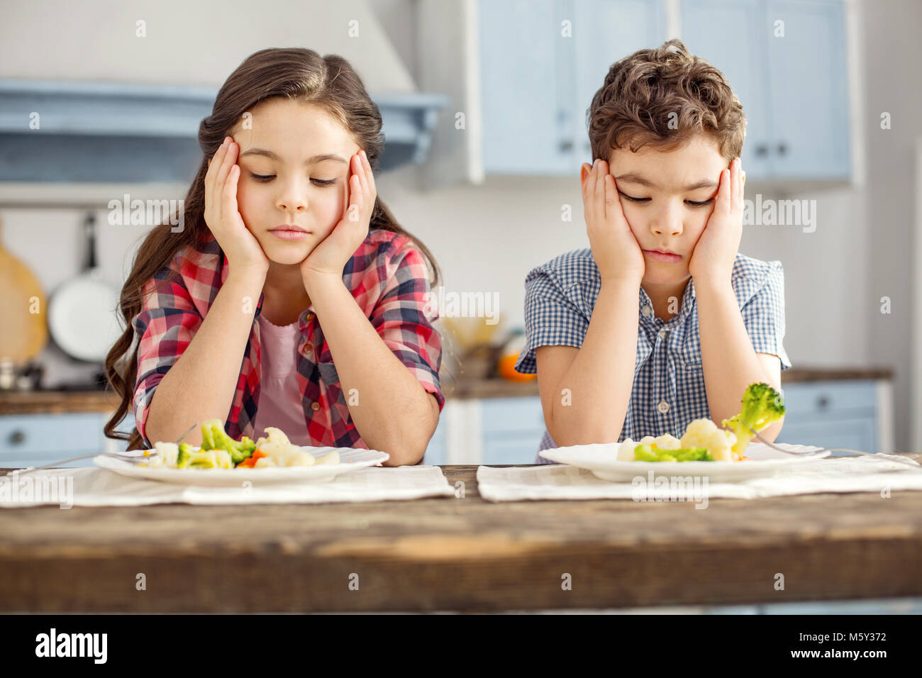Upset siblings looking sadly at the vegetables Stock Photo - Alamy