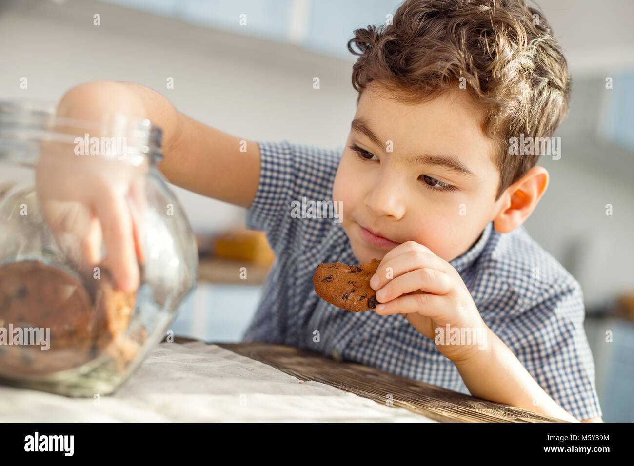Smiling little boy eating some cookies Stock Photo - Alamy