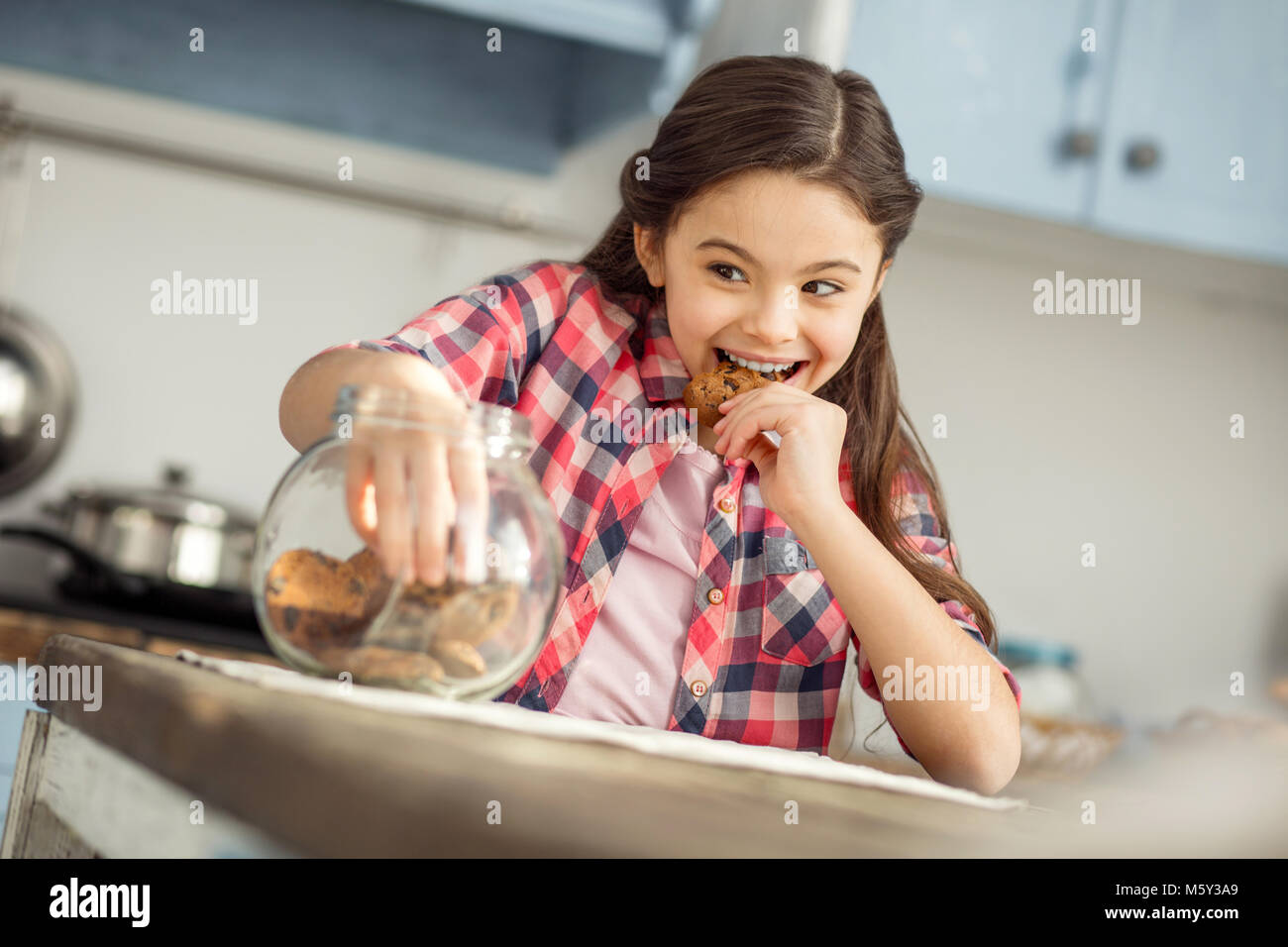 Happy little girl eating some cookies Stock Photo - Alamy