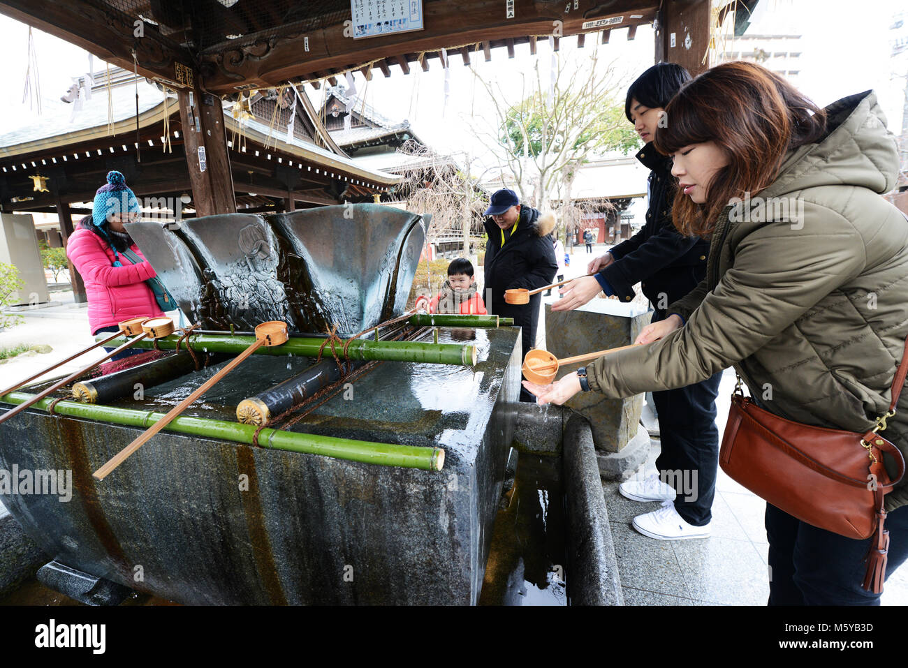 A Japanese woman performing temizu rite - purifying her hands at the ...