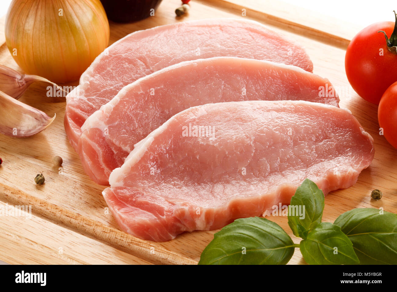 Raw pork chops on cutting board and vegetables Stock Photo - Alamy