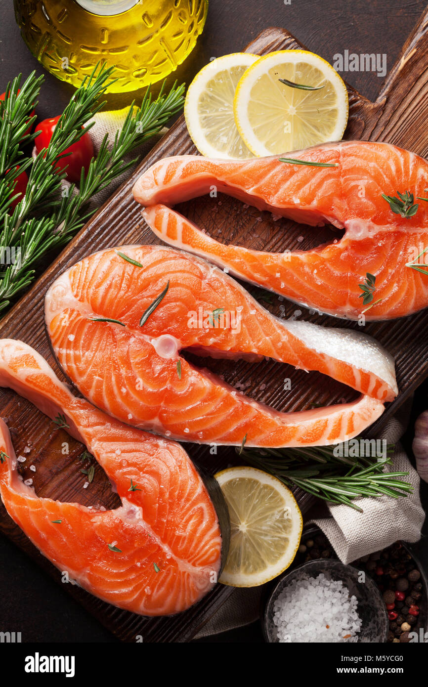 Raw salmon fish fillet with spices cooking on cutting board. Top view ...