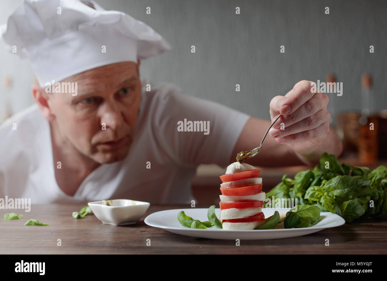 Chef prepares a snack with mozzarella and pesto sauce . Selective focus ...