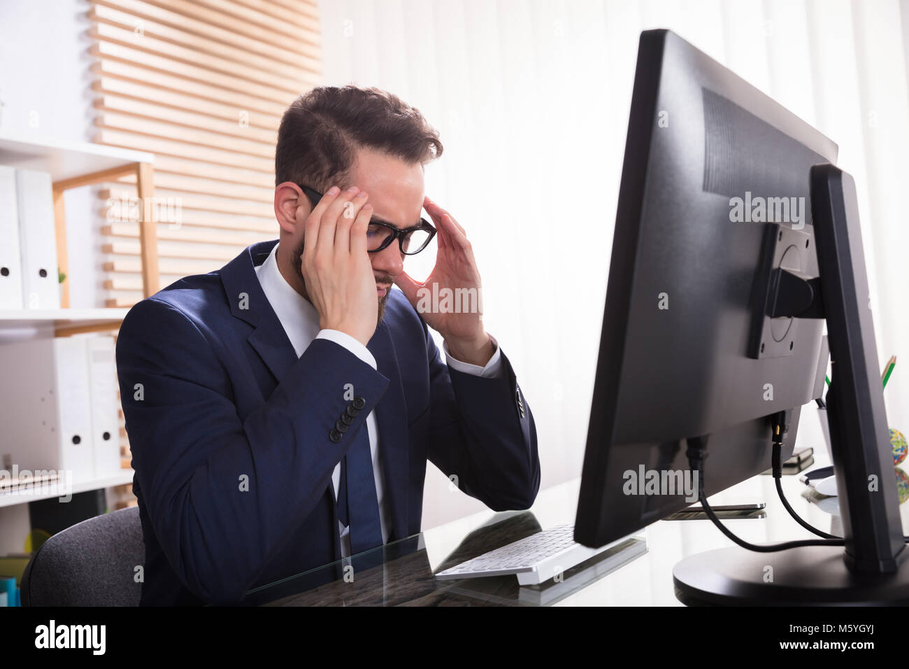 Young Businessman Suffering From Headache Sitting In Front Of Computer ...