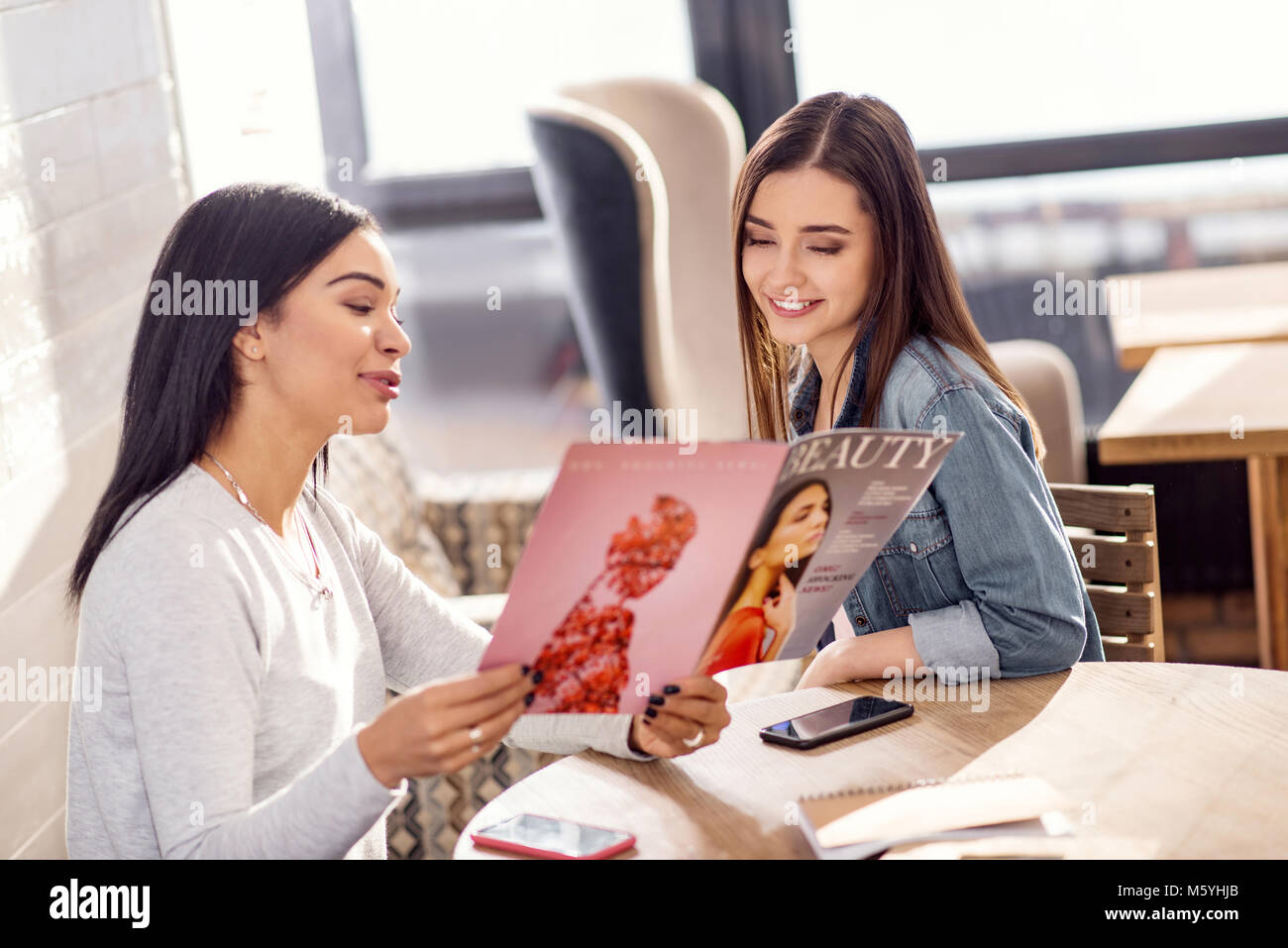 Attractive two friends reading article Stock Photo - Alamy