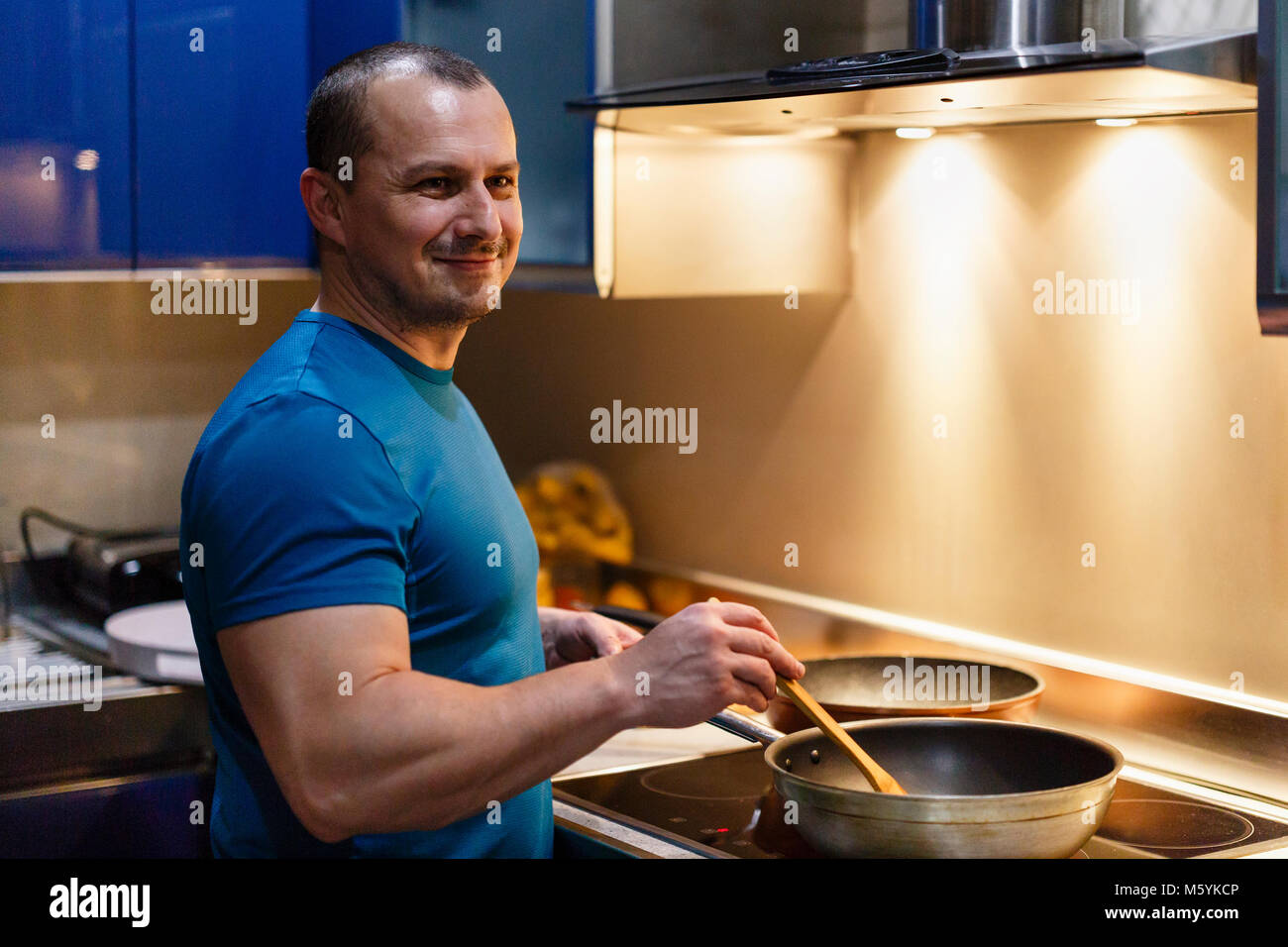 The man in the kitchen is cooking at home at the wok Stock Photo - Alamy
