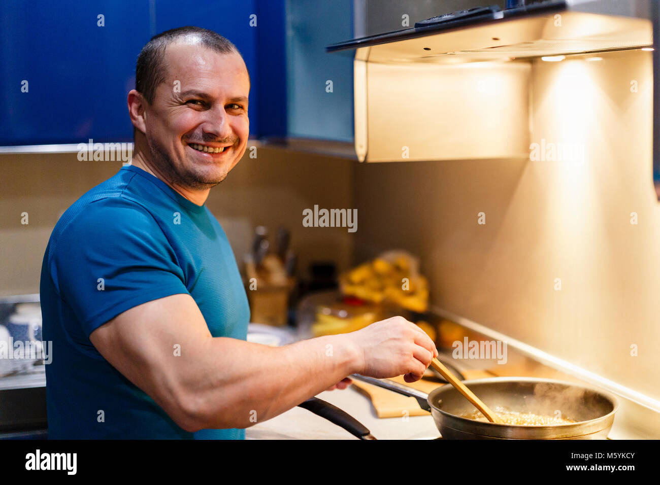 The man in the kitchen is cooking at home at the wok Stock Photo - Alamy