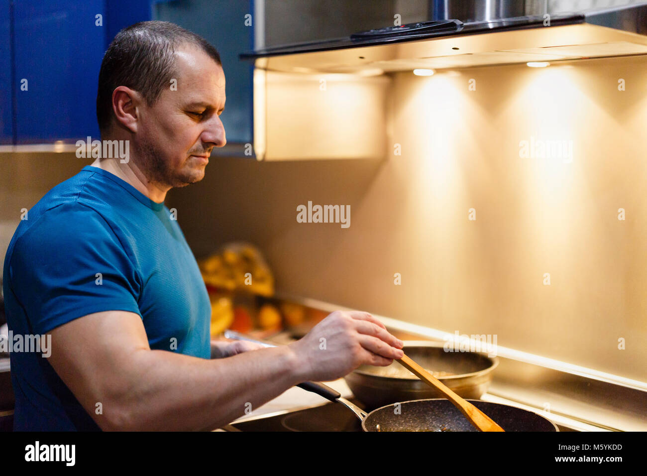 The man in the kitchen is cooking at home at the wok Stock Photo - Alamy