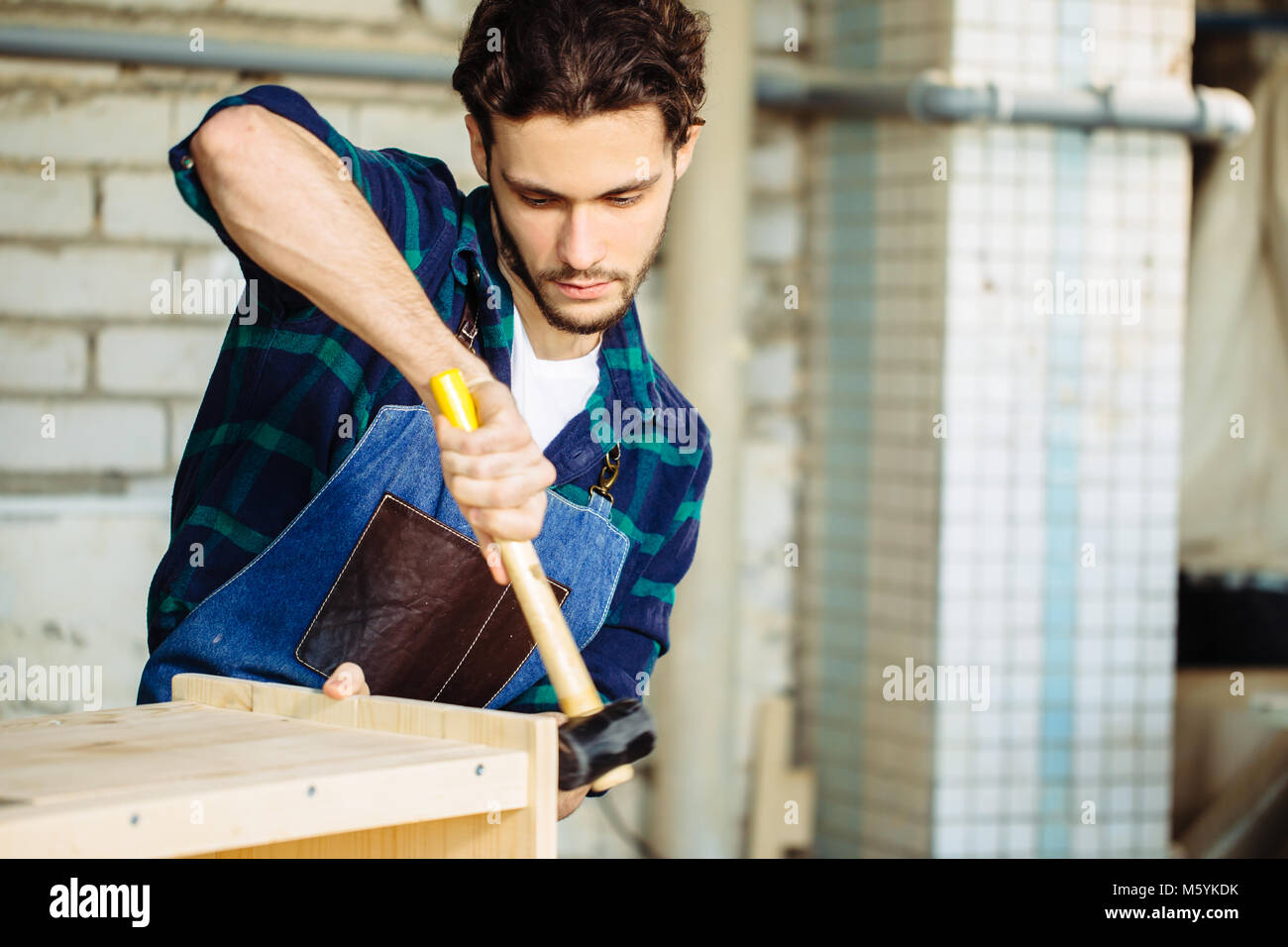 carpenter hammering a nail into wooden board Stock Photo - Alamy