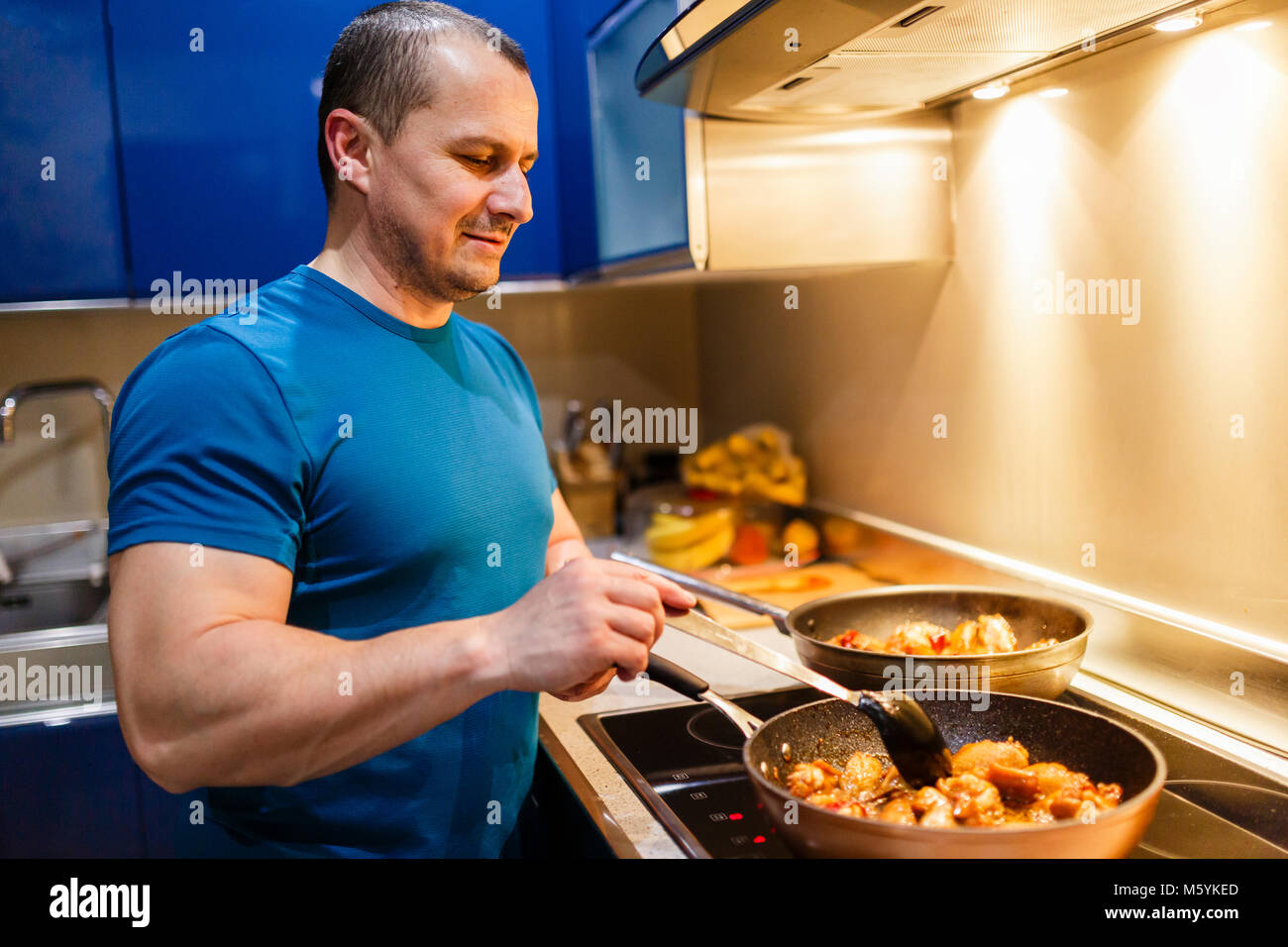 The man in the kitchen is cooking at home at the wok Stock Photo - Alamy
