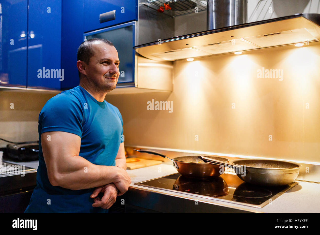 The man in the kitchen is cooking at home at the wok Stock Photo - Alamy