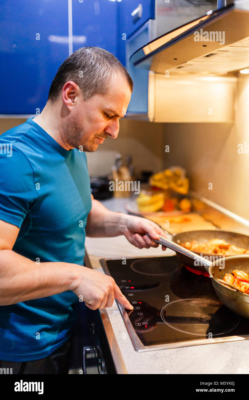 The man in the kitchen is cooking at home at the wok Stock Photo - Alamy