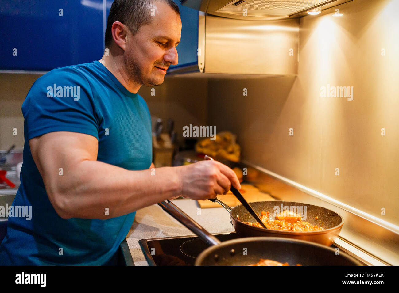 The man in the kitchen is cooking at home at the wok Stock Photo - Alamy