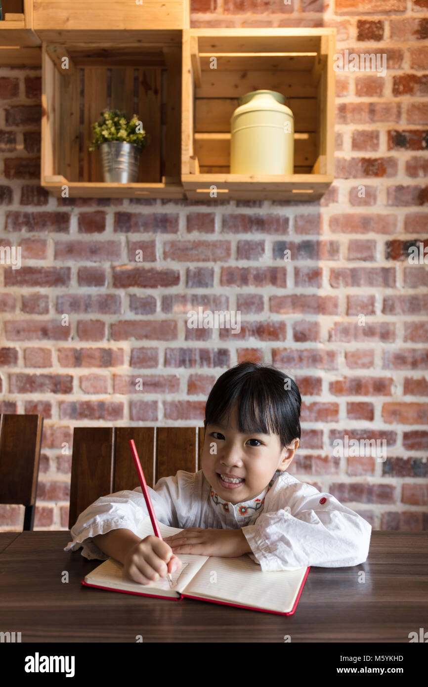 Asian Chinese little girl doing homework at indoor cafe Stock Photo - Alamy