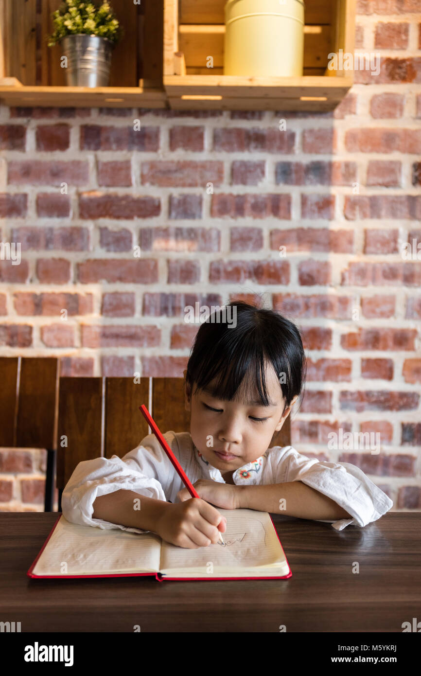 Asian Chinese little girl doing homework at indoor cafe Stock Photo - Alamy