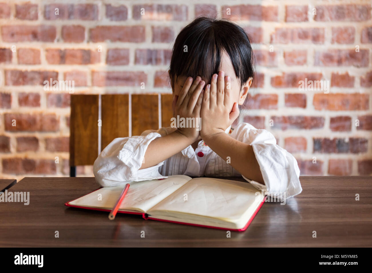 Frustrated Asian chinese little girl doing homework at home Stock Photo ...