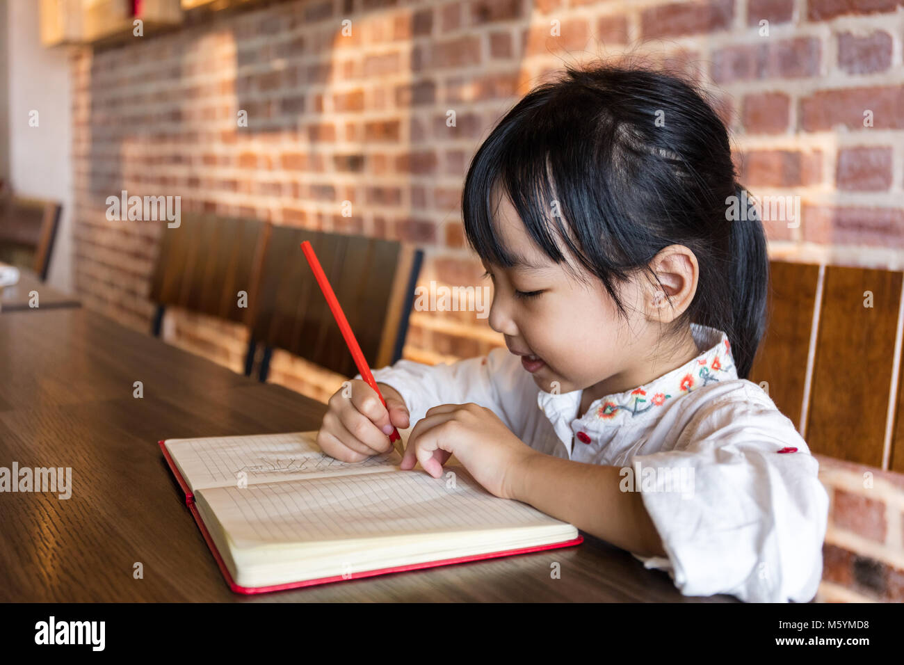 Asian Chinese little girl doing homework at indoor cafe Stock Photo - Alamy