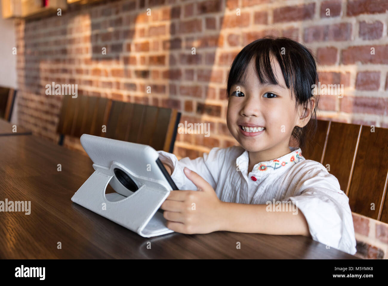 Asian Chinese little girl playing tablet computer at indoor cafe Stock ...