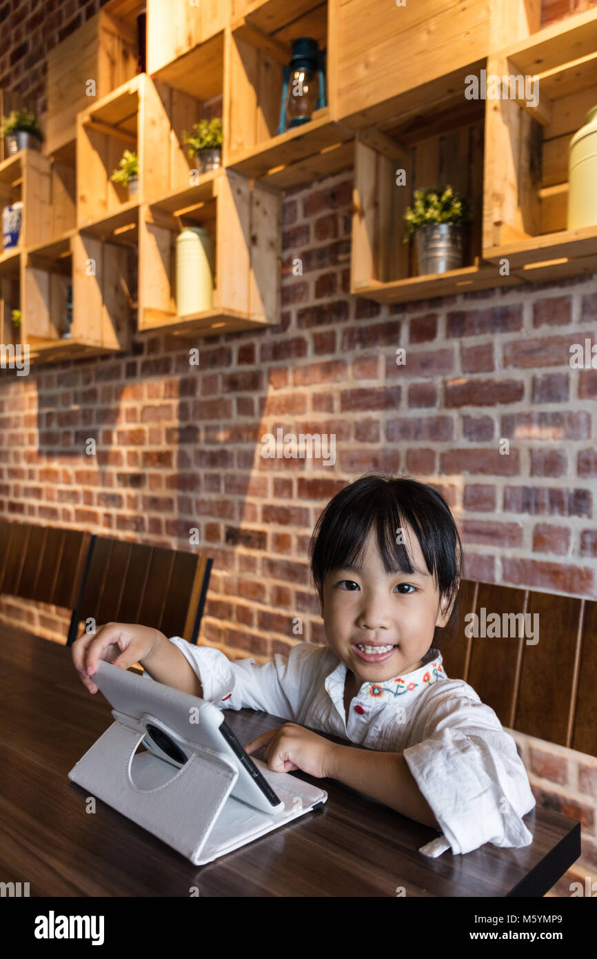 Asian Chinese little girl playing tablet computer at indoor cafe Stock ...