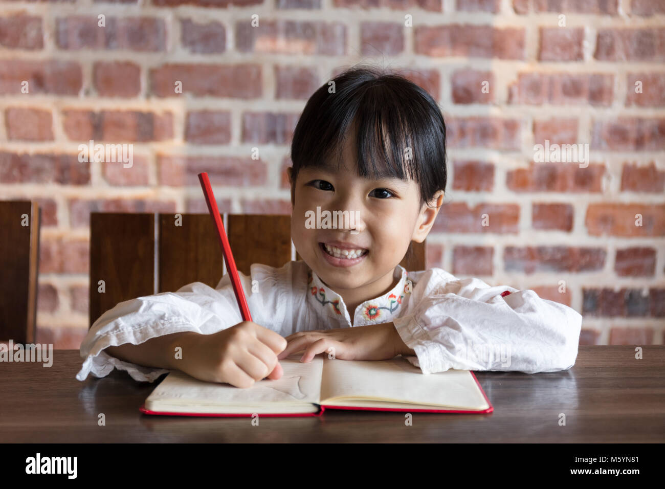 Asian Chinese little girl doing homework at indoor cafe Stock Photo - Alamy