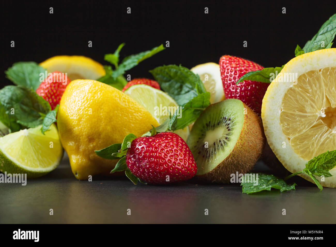 Different juicy fruits and mint leaves on black background Stock Photo ...