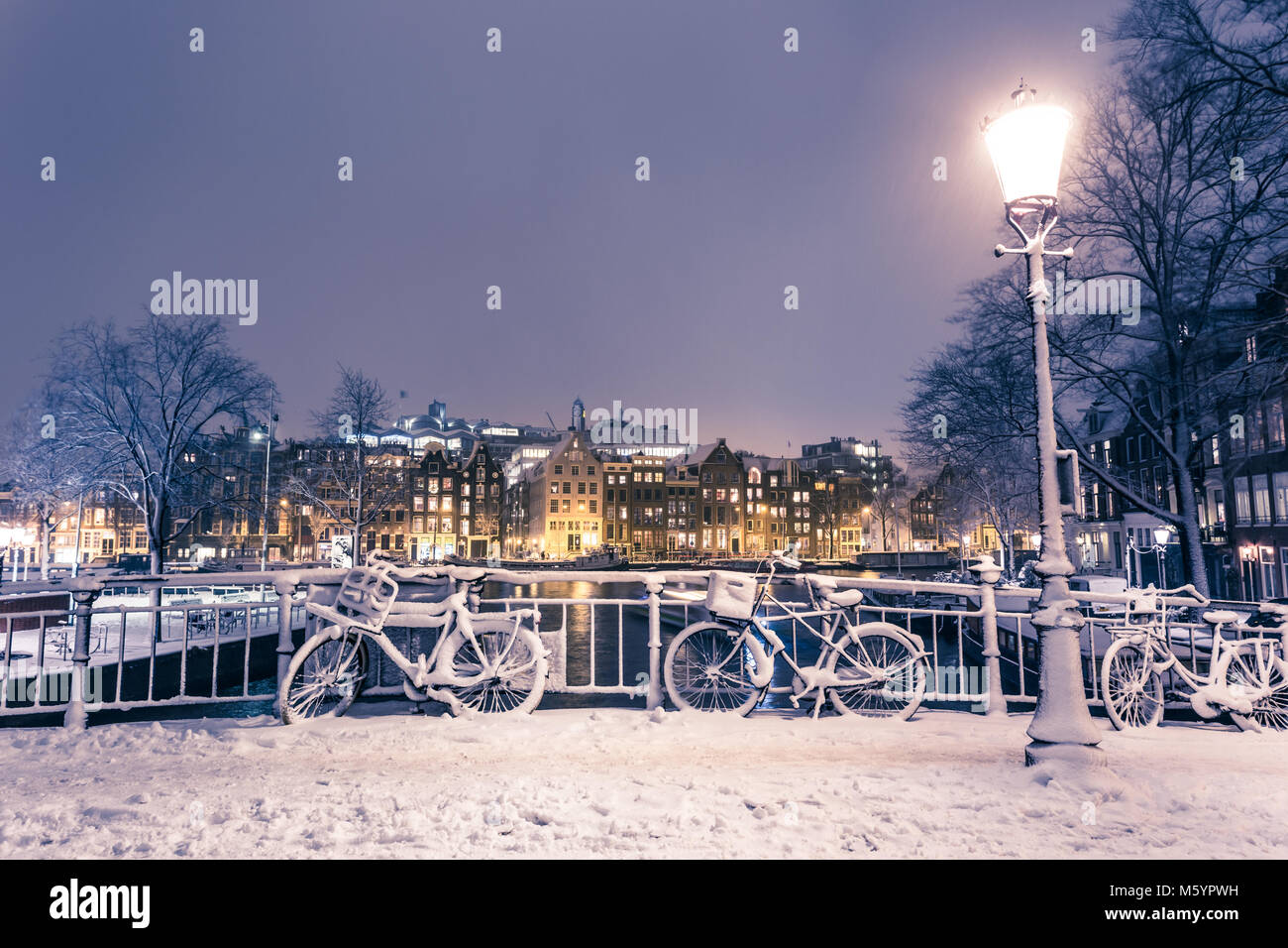 Bicycles under snow on the bridge over Amstel river in Amsterdam in the ...