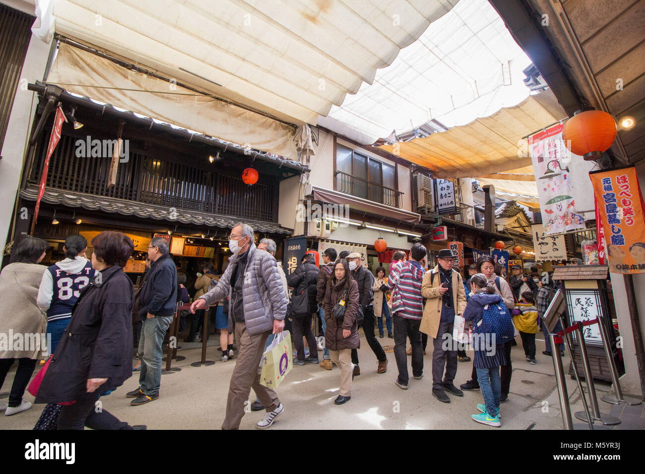 People walking through the old town shops in Miyajima. The shops sell ...