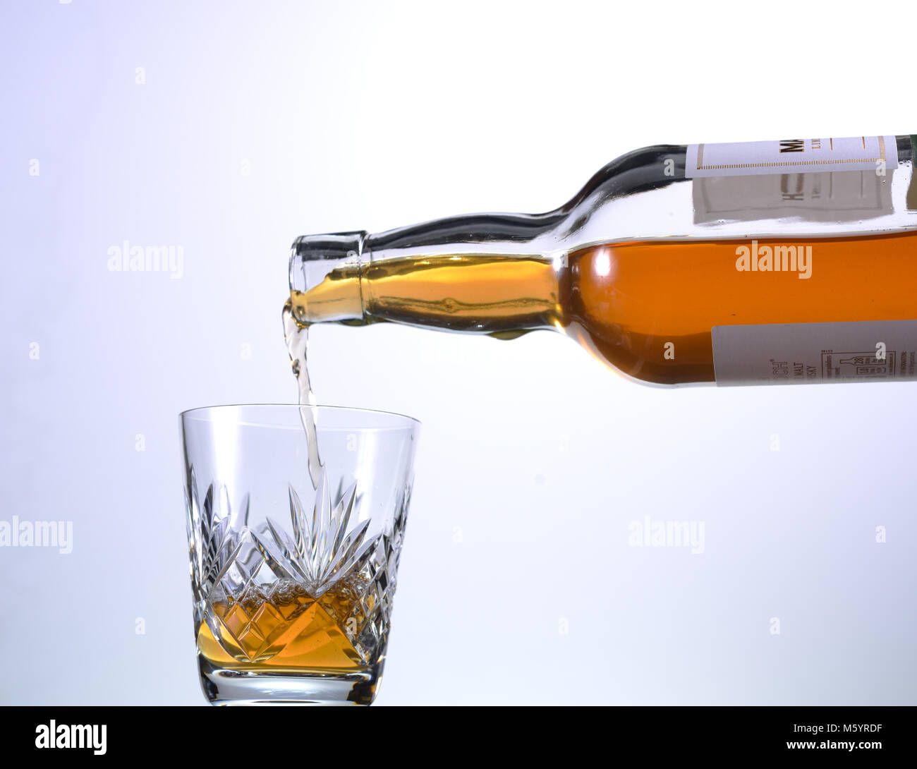 Whiskey being poured into ornate glass with white background Stock ...