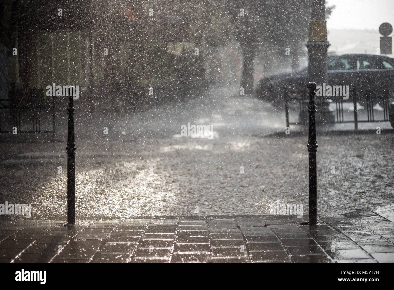 Rain in the city. Road, pavement, car in rain, close up. Water splashes ...