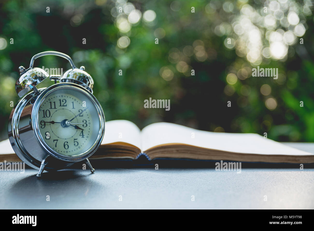 Open book with alarm clock. Book open on old wooden table on nature ...