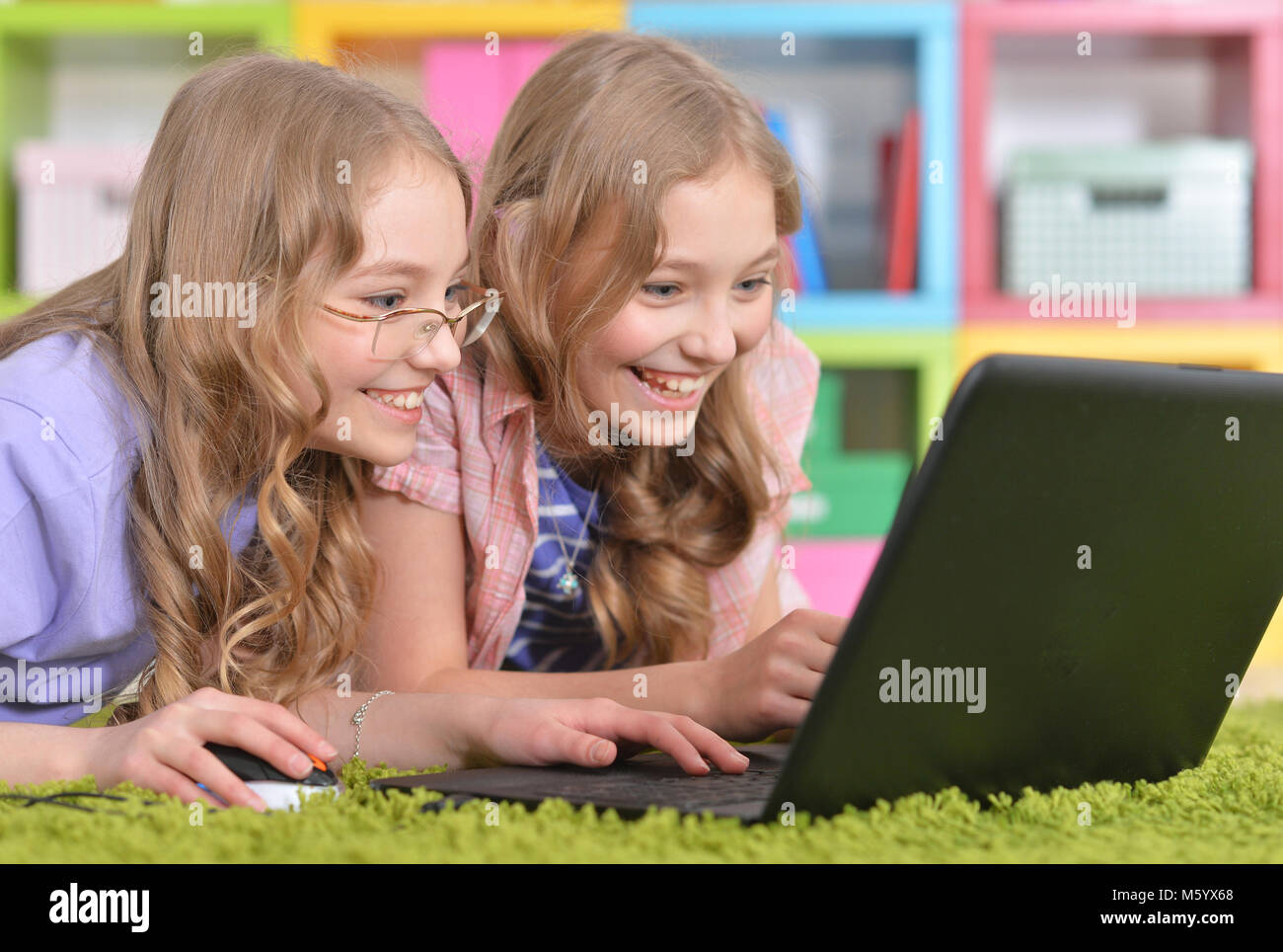 Teenagers sisters using laptop Stock Photo - Alamy