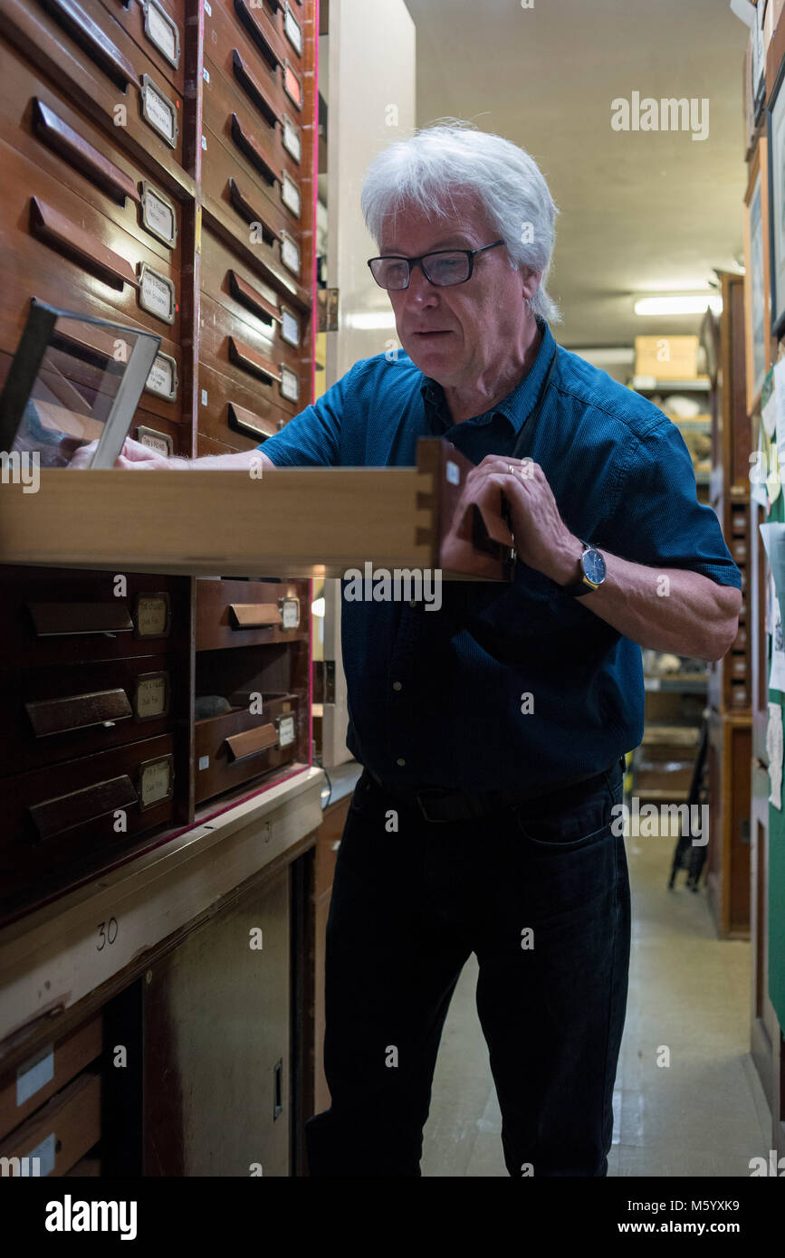 a museum worker poses amongst the collection and archive of the booth ...