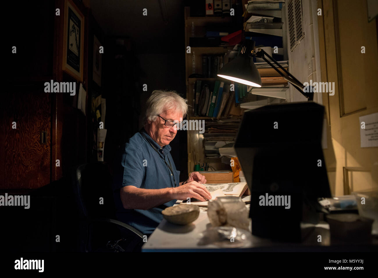 a museum worker poses amongst the collection and archive of the booth ...