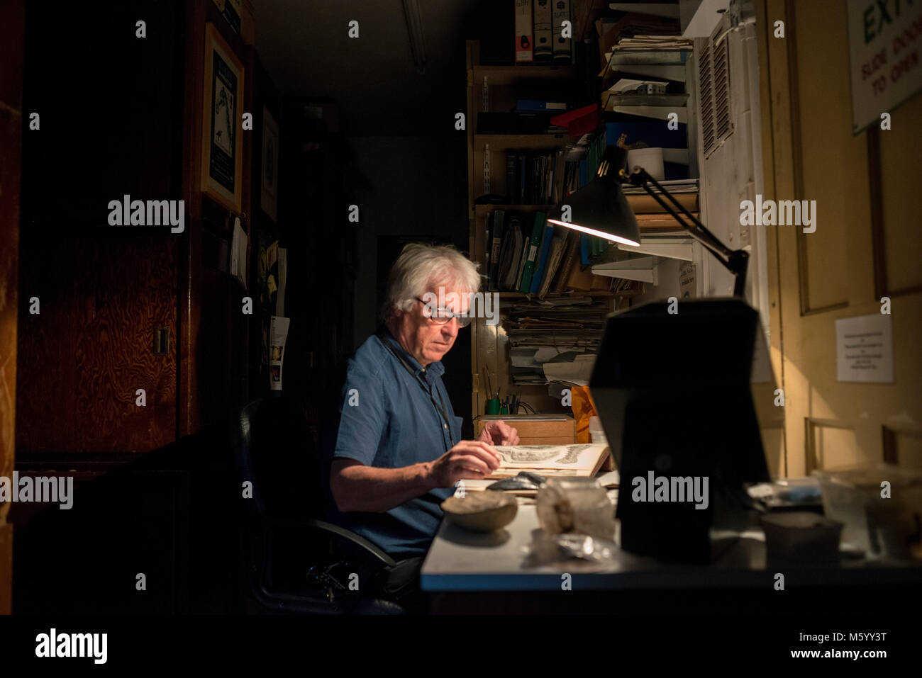 a museum worker poses amongst the collection and archive of the booth ...