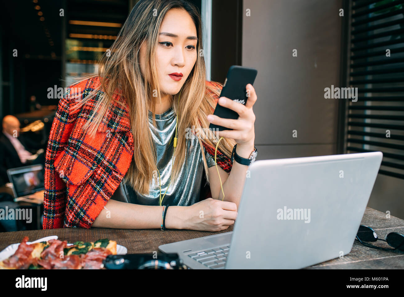 young woman outdoor sitting using laptop computer and smart phone ...