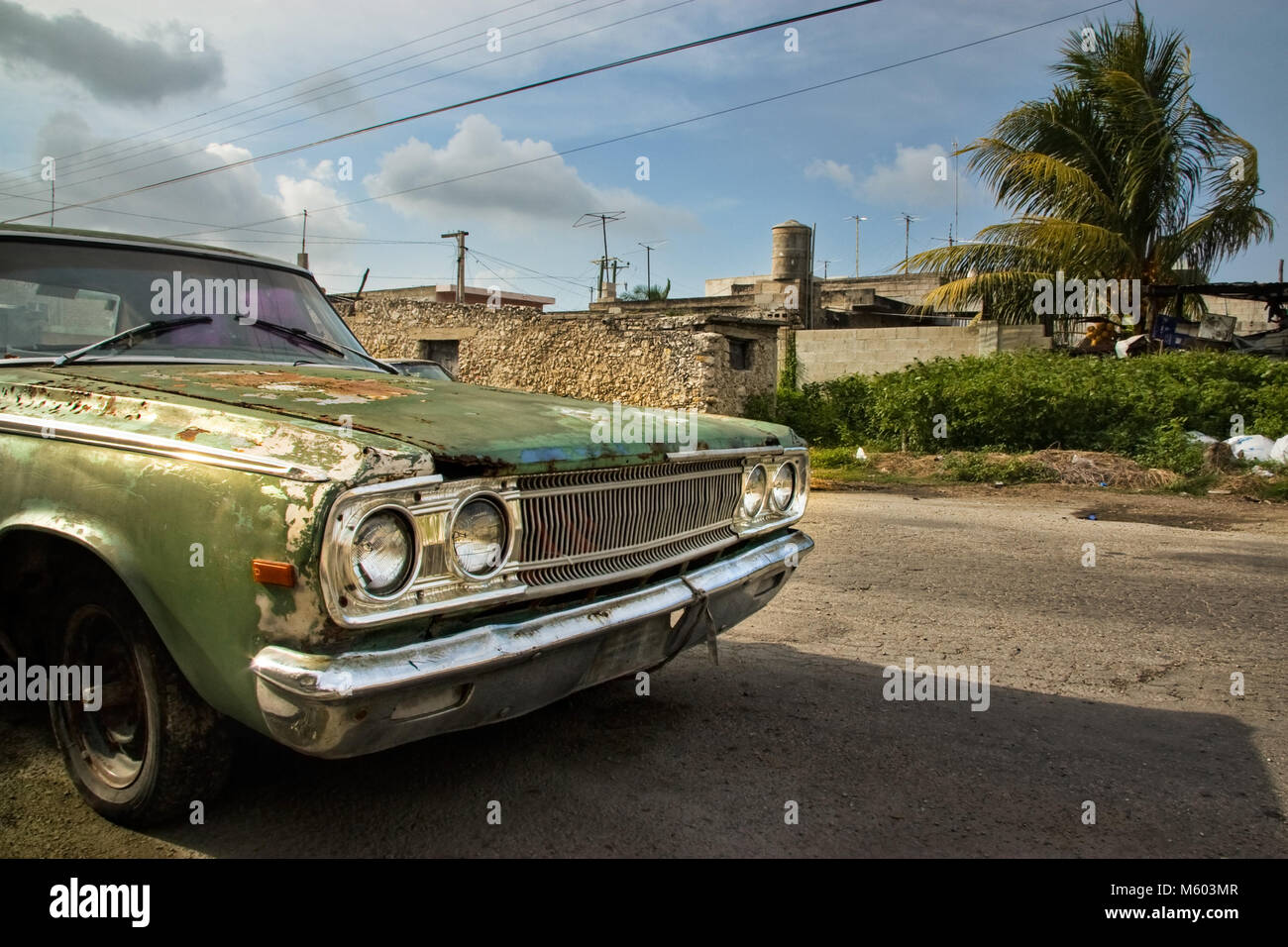 Front of old rusty faded green car on empty road during summer day ...