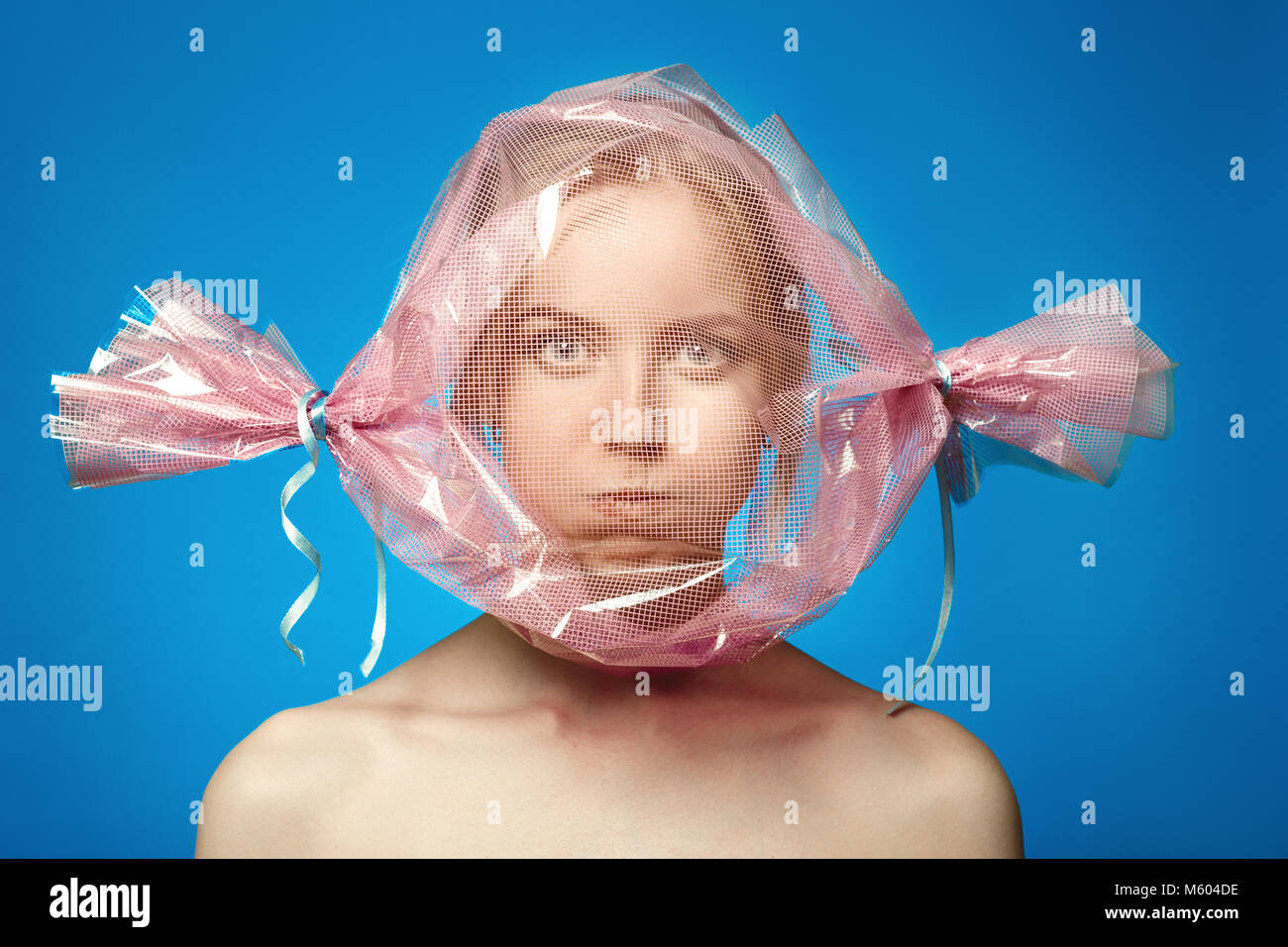 fun girl with head inside candy wrapper on blue background Stock Photo ...