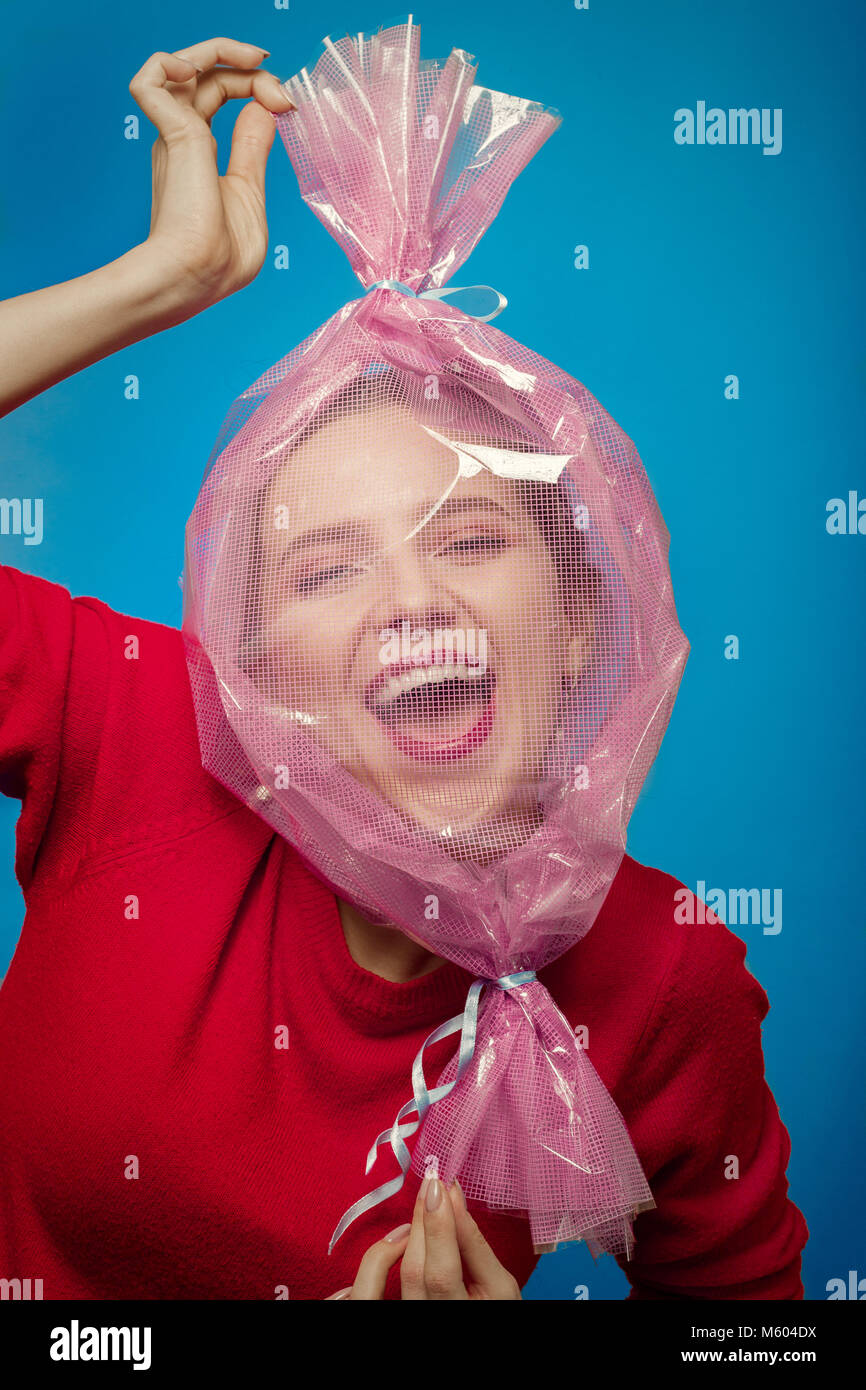fun girl with head inside candy wrapper on blue background Stock Photo ...