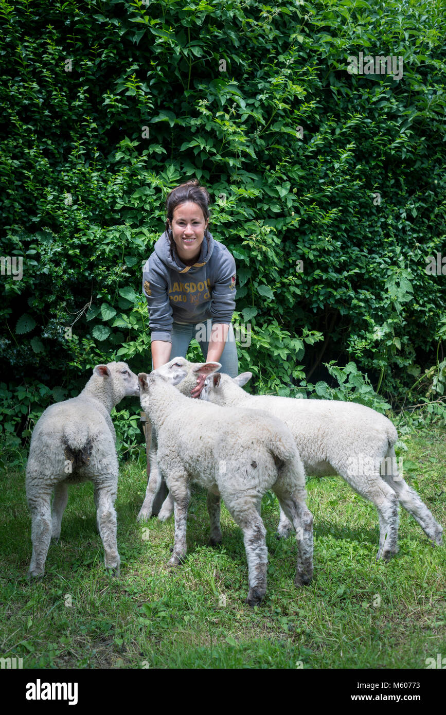 a young female farmer looks after and feeds while posing with some ...
