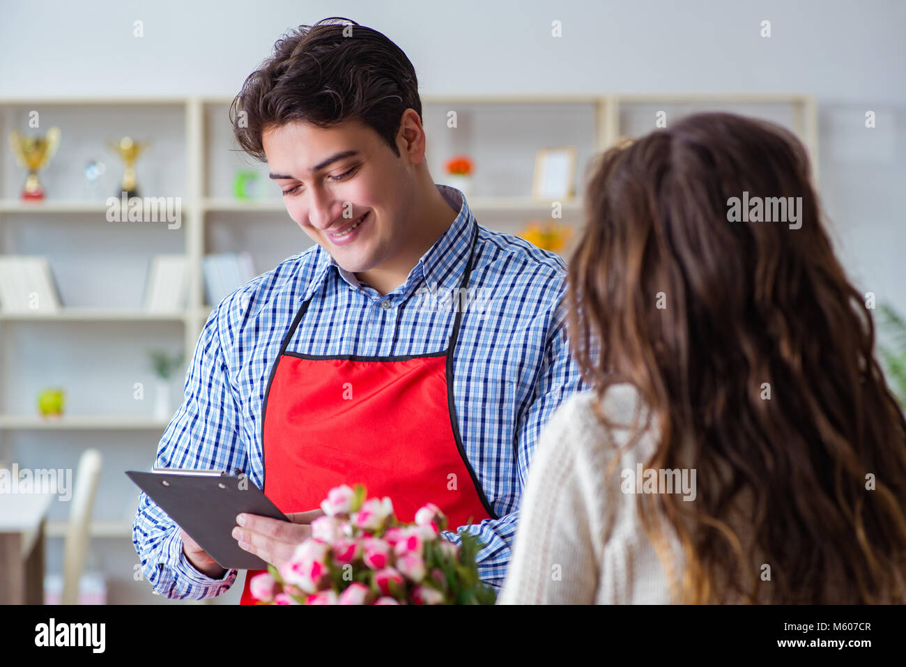 Flower shop assistant selling flowers to female customer Stock Photo ...