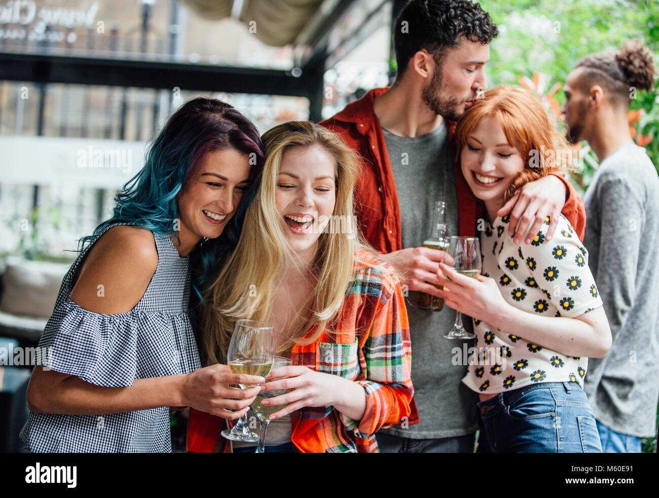Friends are laughing together while enjoying drinks in a bar courtyard ...