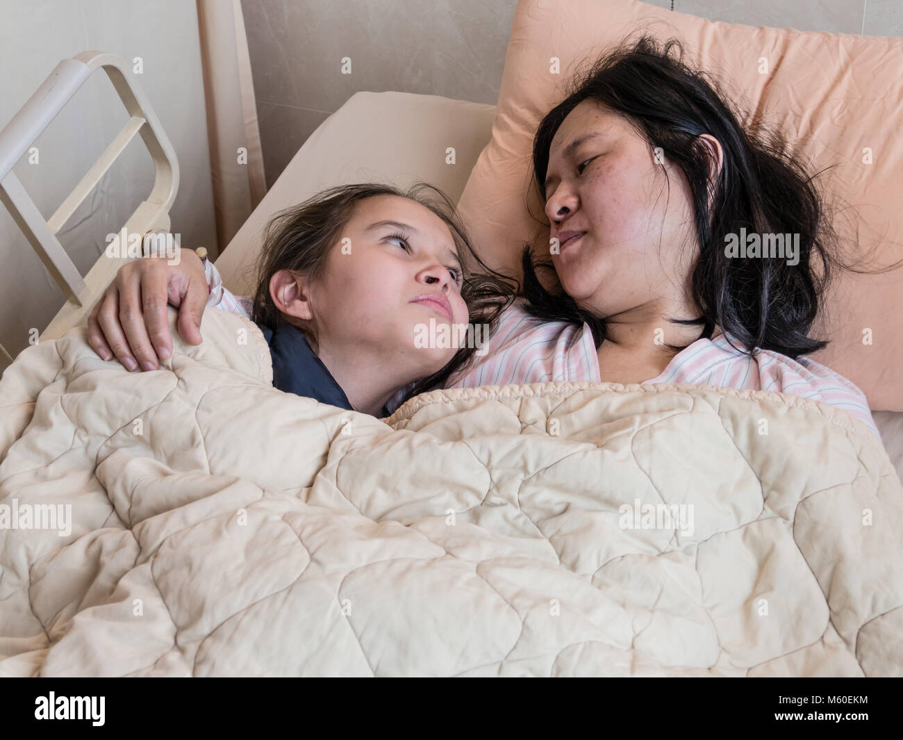 Girl lying on hospital bed next to sick mother, family health care ...